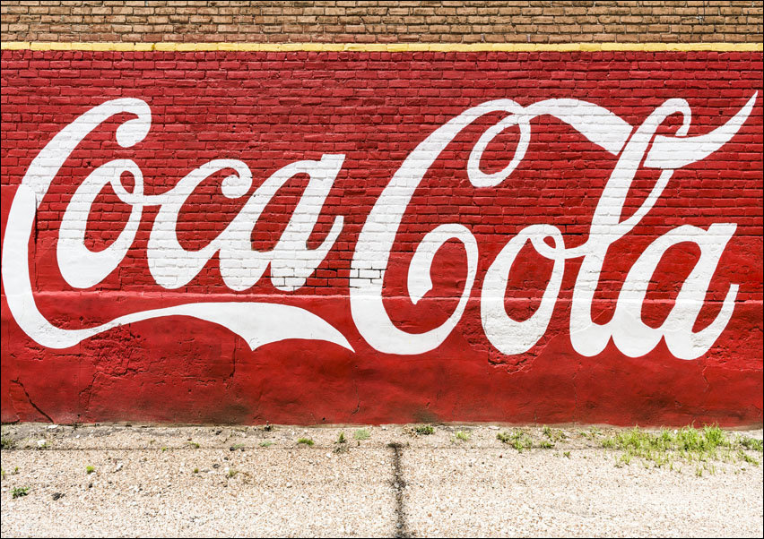 An old, painted Coca-Cola sign on the side of a building in the town of ...
