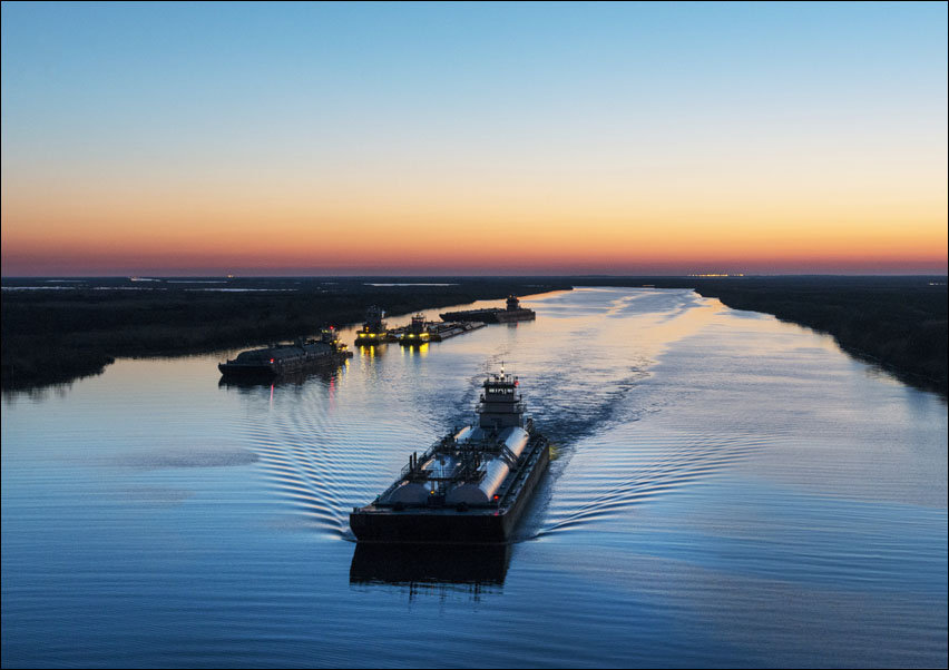 Dusk shot of barges traversing a short canal that connects the Sabine ...
